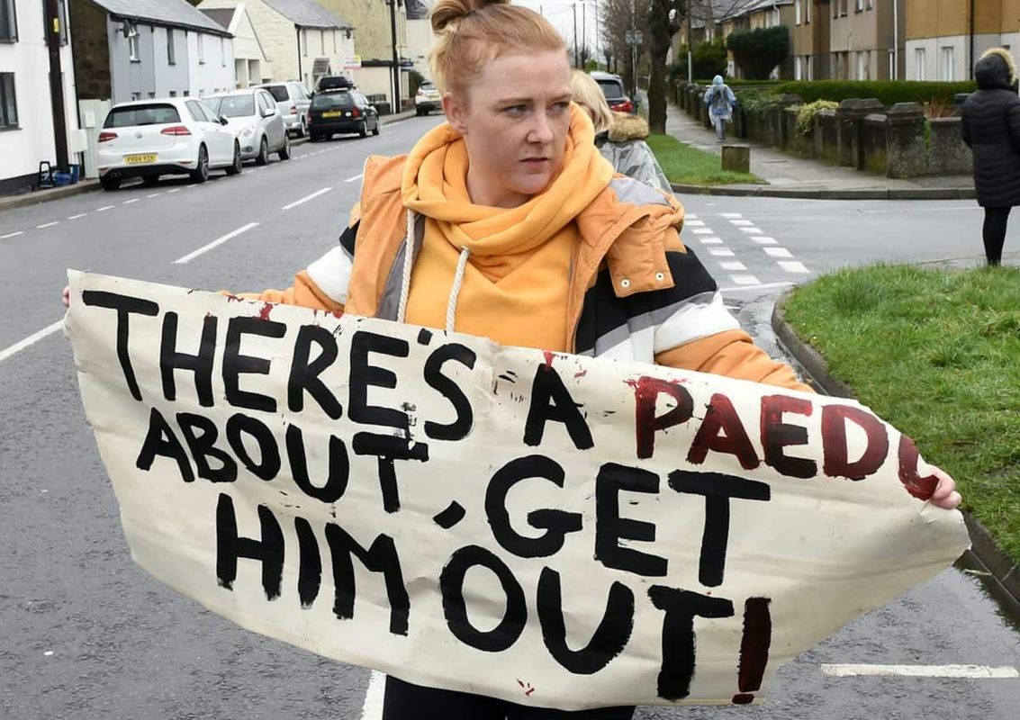 Protesters wave signs including ‘Watch out, there’s a paedo about ...