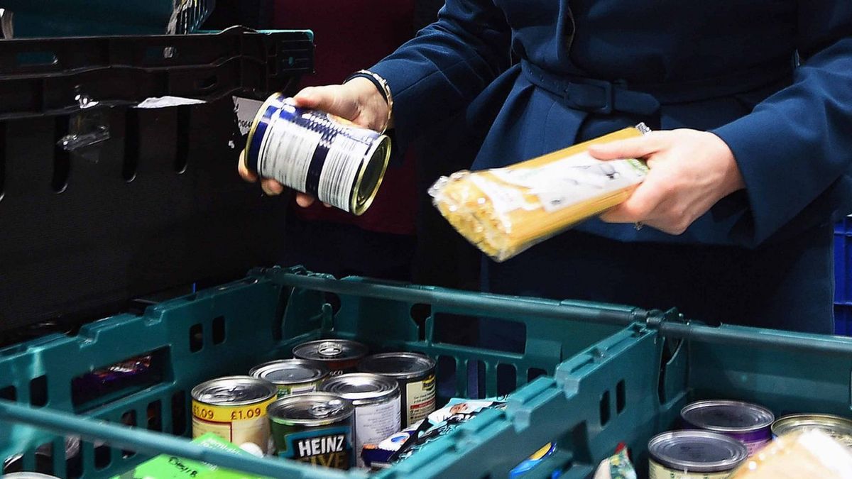 Tory mayor in gold chain smiles as she cuts the ribbon on a new food bank